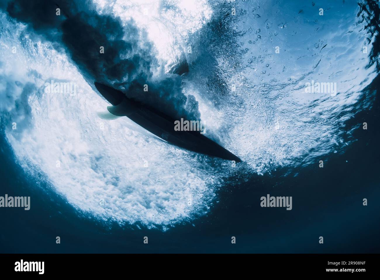 Surfer on surfboard in ocean underwater view. Crashing wave and ...