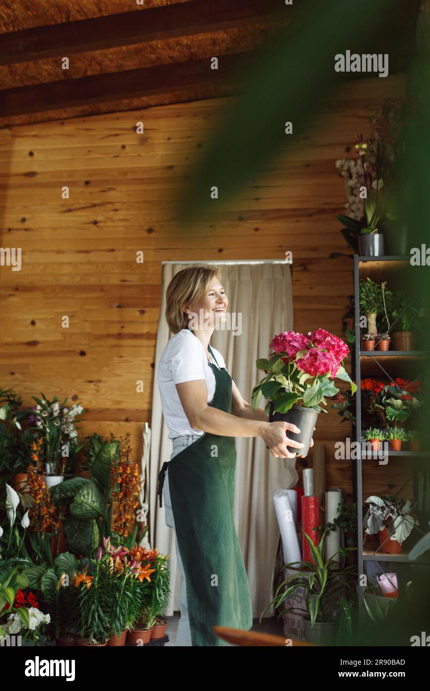 Portrait of smiling young botanist holding a fresh flower plant. Young ...