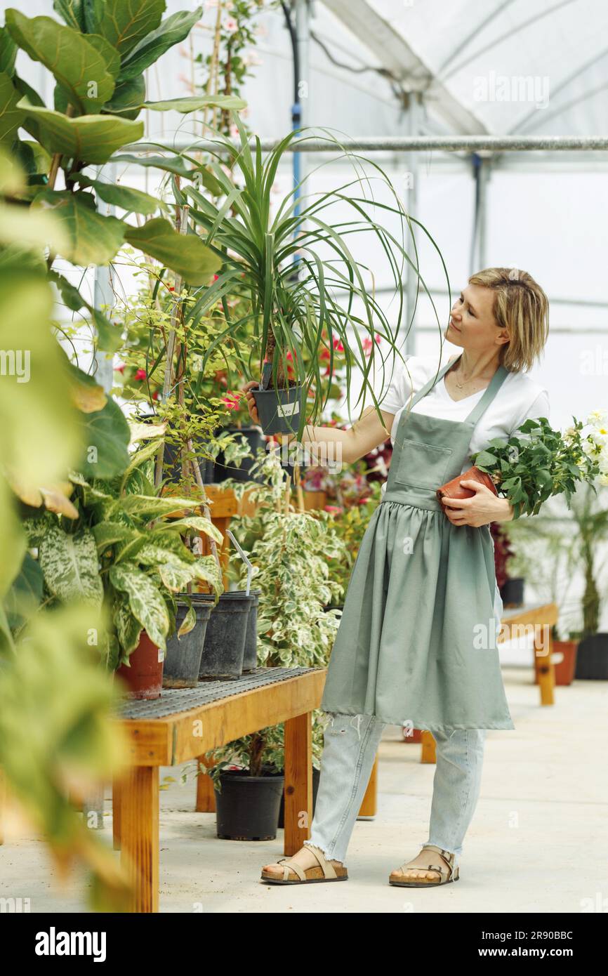 Portrait of smiling young botanist holding a fresh flower plant. Young ...
