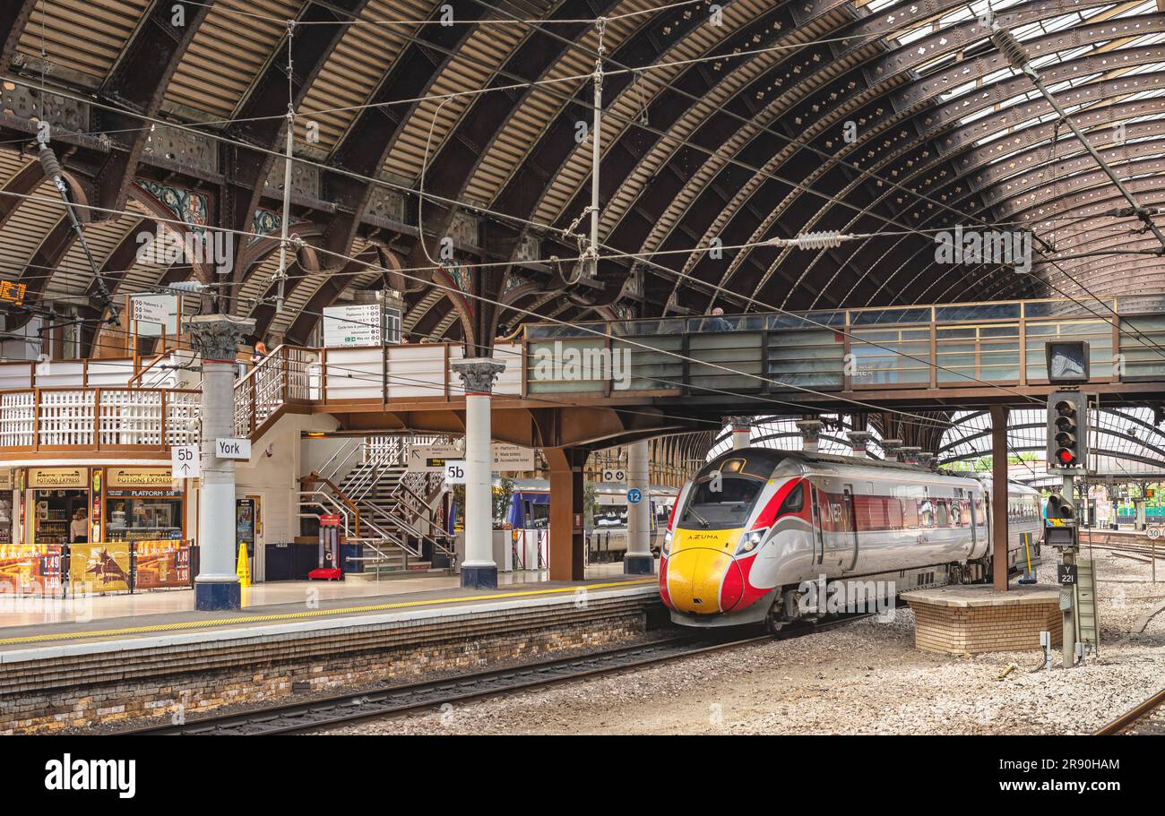 A train arrives at a platform of a railway station with a footbridge ...