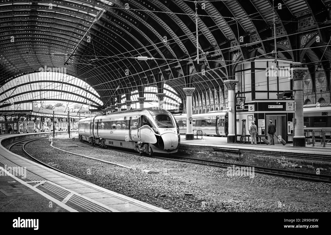 A sleek modern locomotive stands at railway station platform and a 19th ...