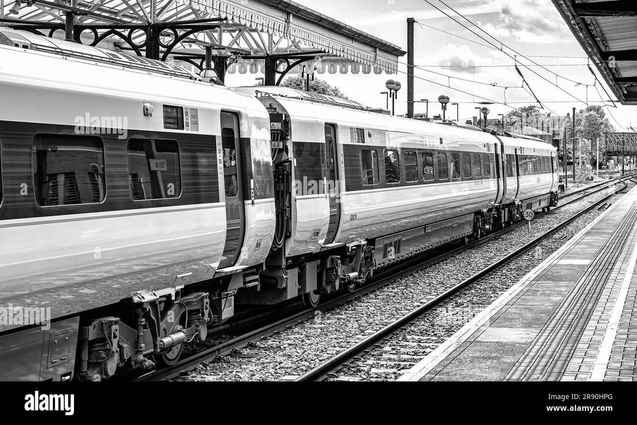 A line of railway carriages stand near a 19th Century historic canopy ...