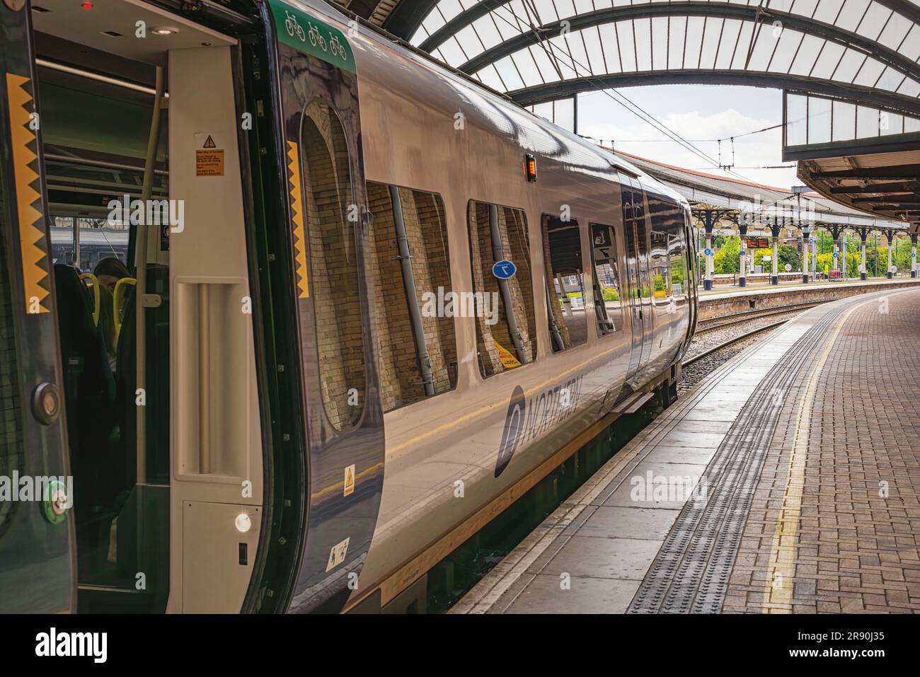 A line of railway carriages stand near a 19th Century historic canopy ...