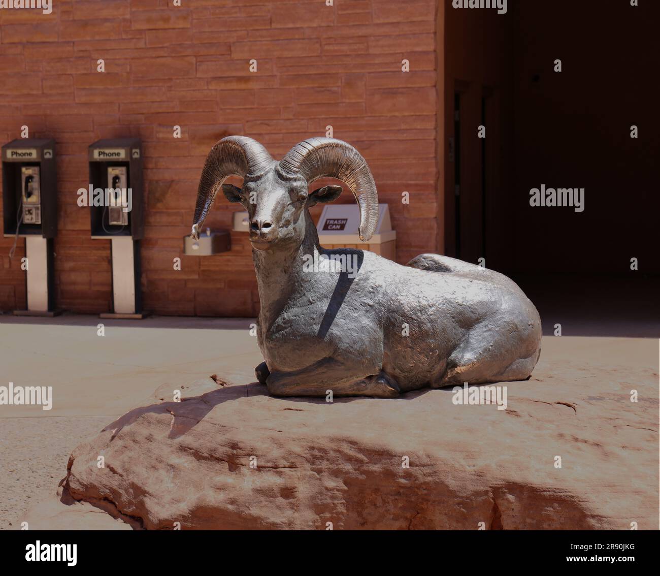 A bronze big horn sheep sculpture sittiing on a sandstone boulder at ...