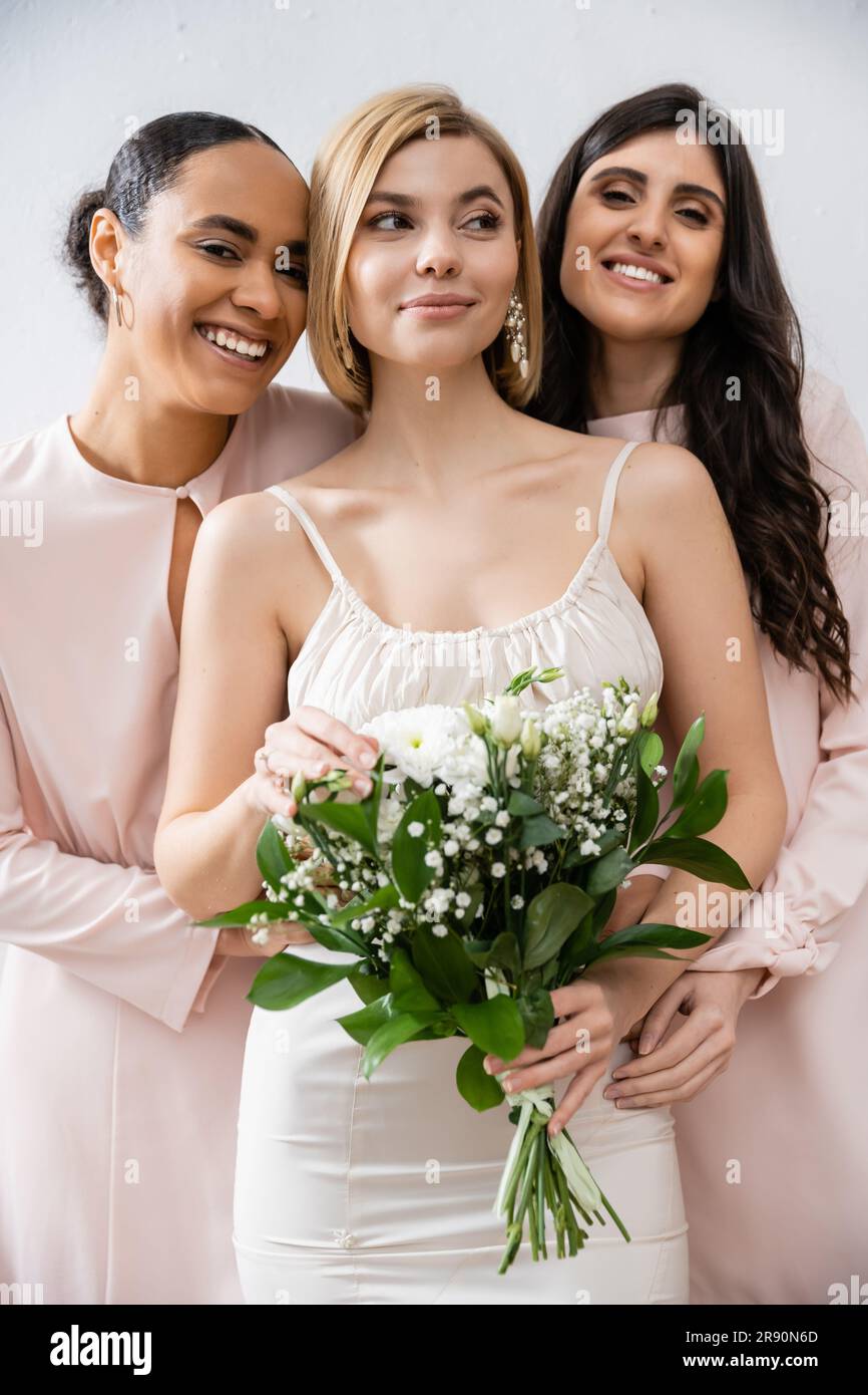 special occasion, brunette and interracial bridesmaids hugging blonde ...