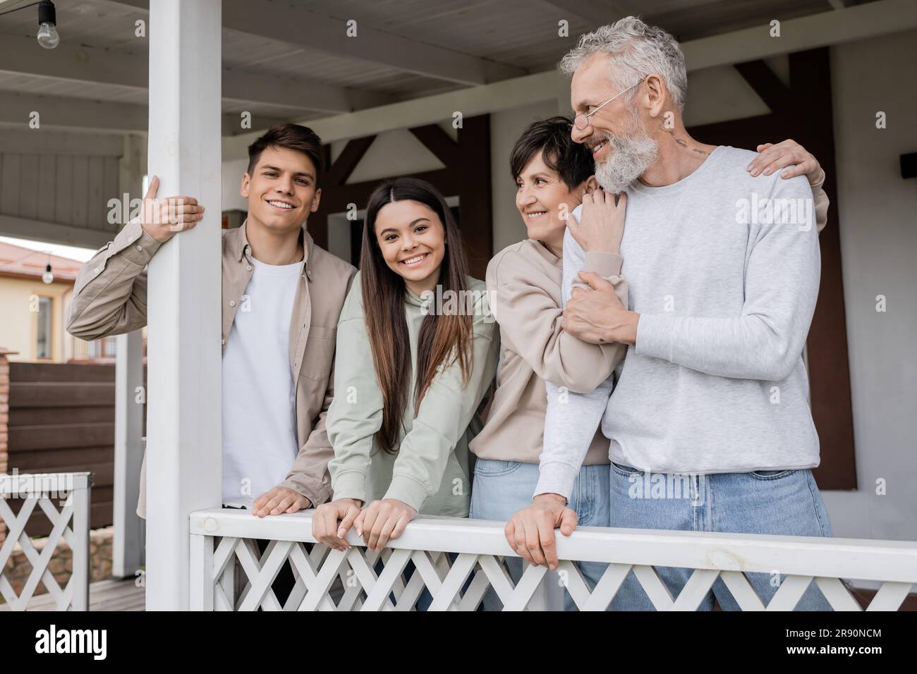 parents day, middle aged parents hugging and looking away near teenage ...