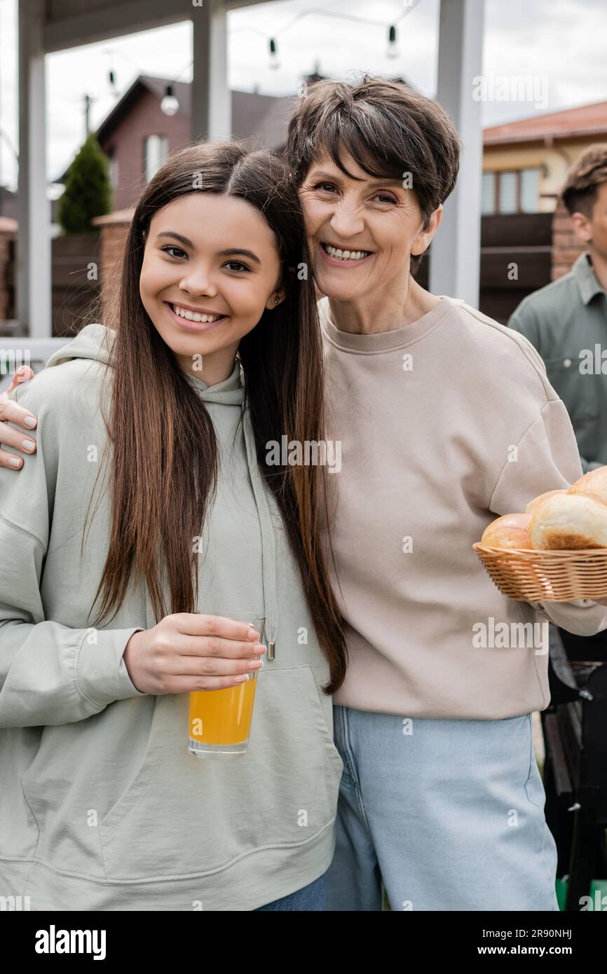 modern parenting, celebration of parents day, happy middle aged mother holding buns and hugging ...