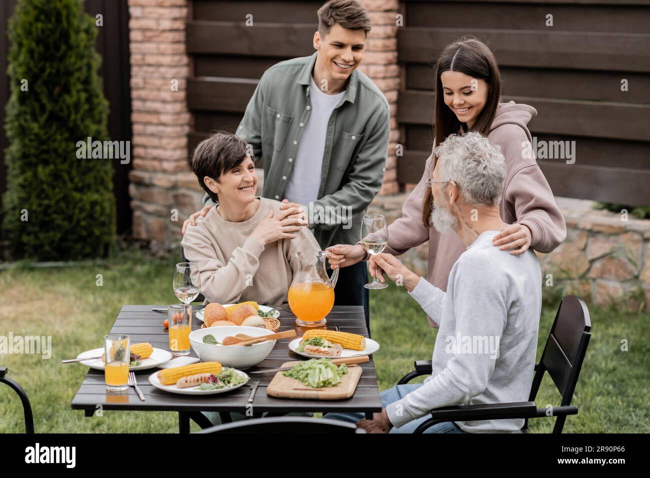 Smiling siblings hugging middle aged parents and spending time together ...