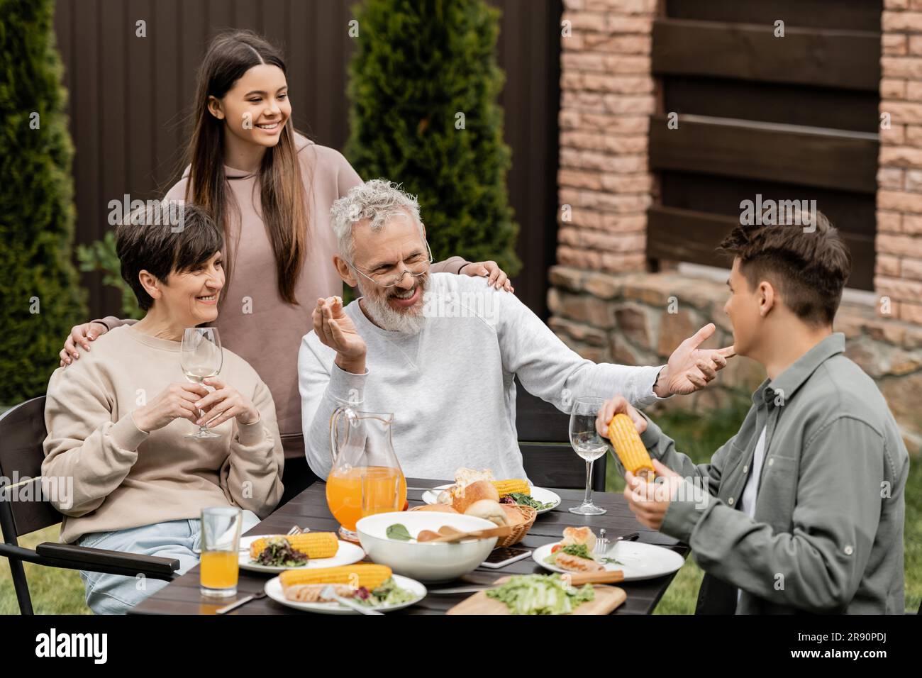 Cheerful middle aged man talking to young soon while sitting near ...