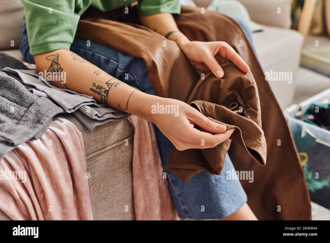 partial view of young and stylish woman with tattooed arms holding ...