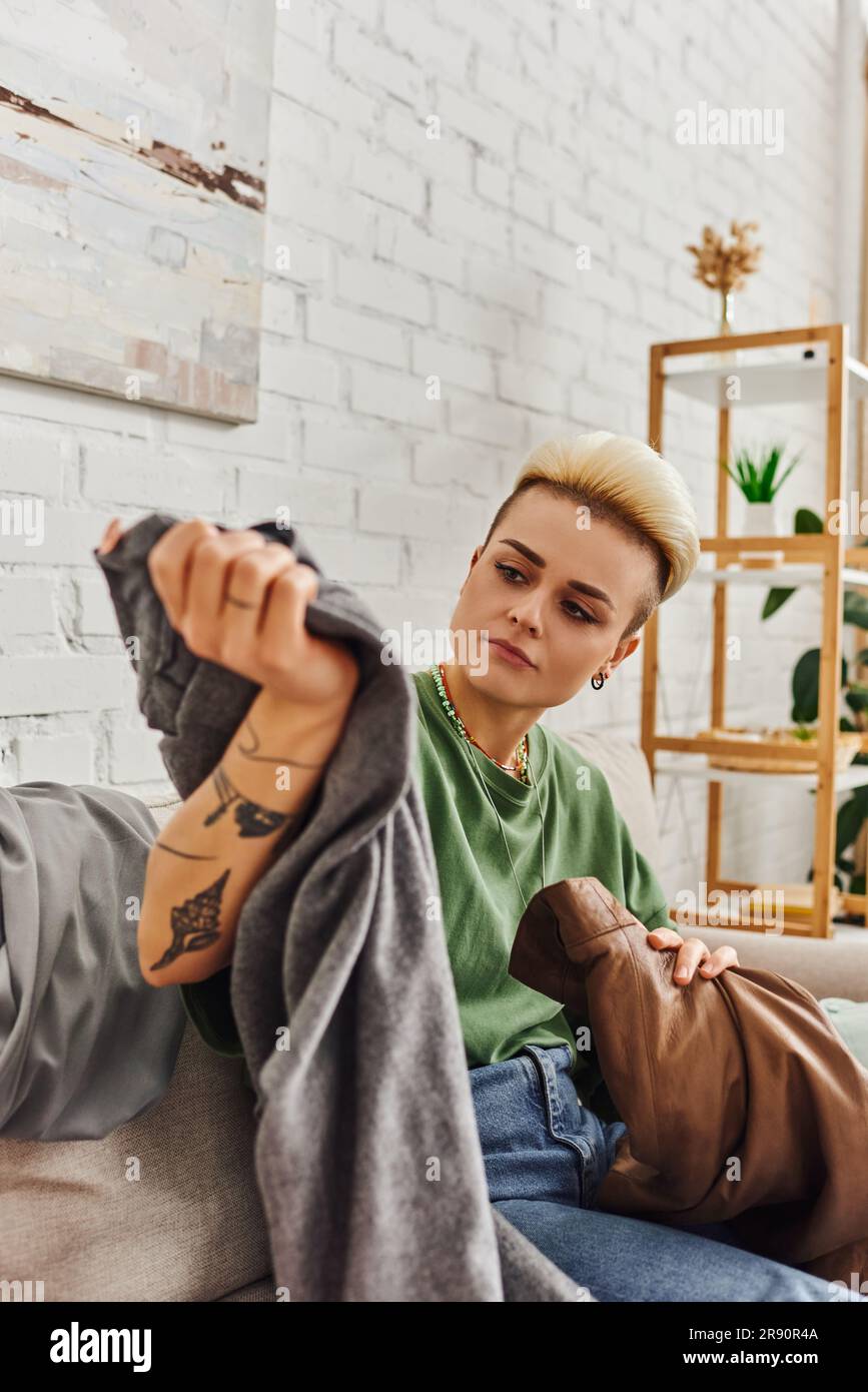 Tattooed Woman With Trendy Hairstyle Sorting Clothes And Reducing