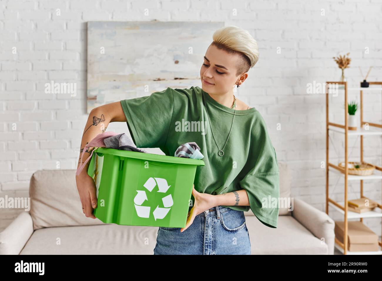 social responsibility, young and tattooed woman holding green recycling ...