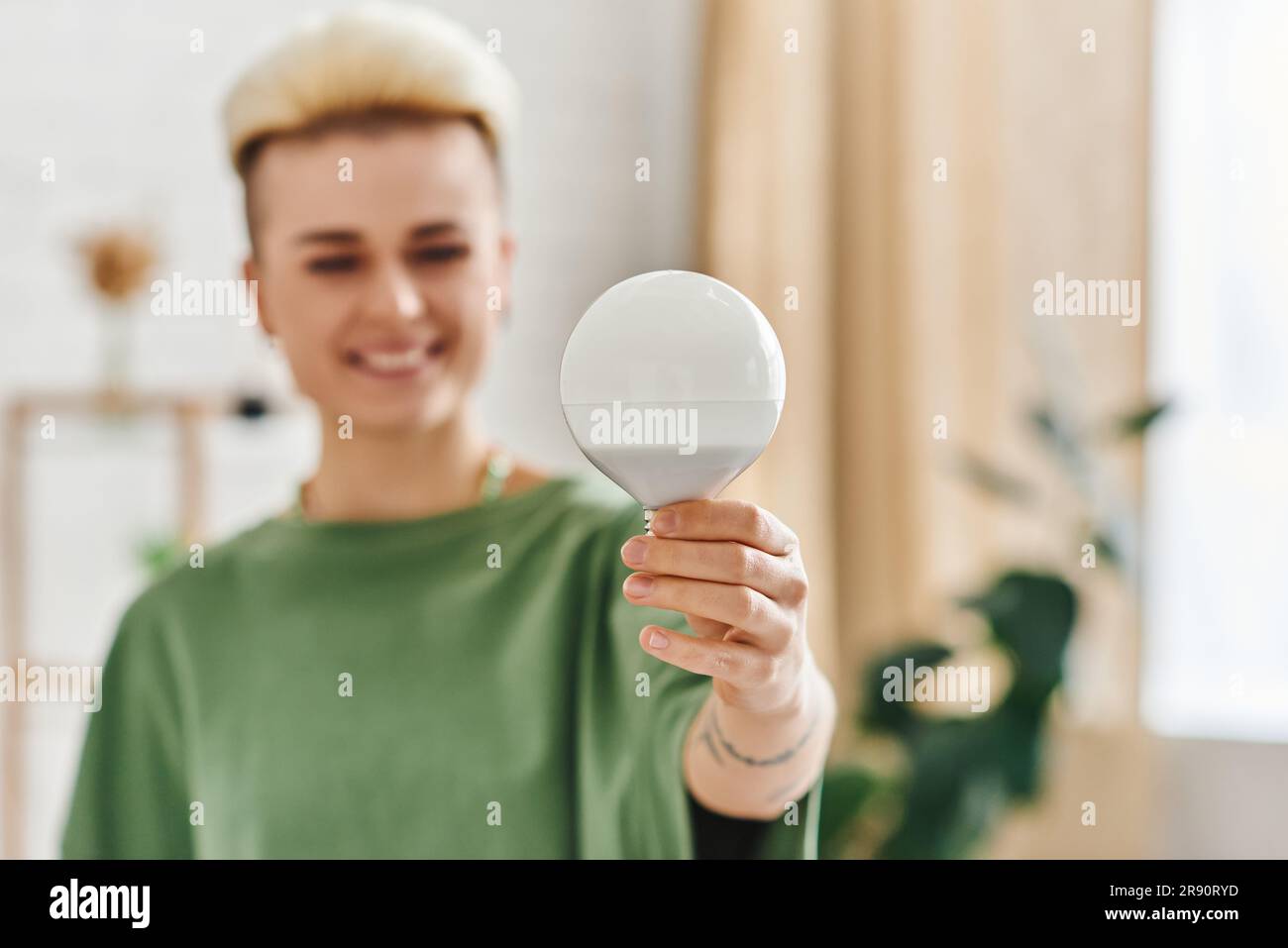 energy saving light bulb in hand of overjoyed young woman with trendy ...