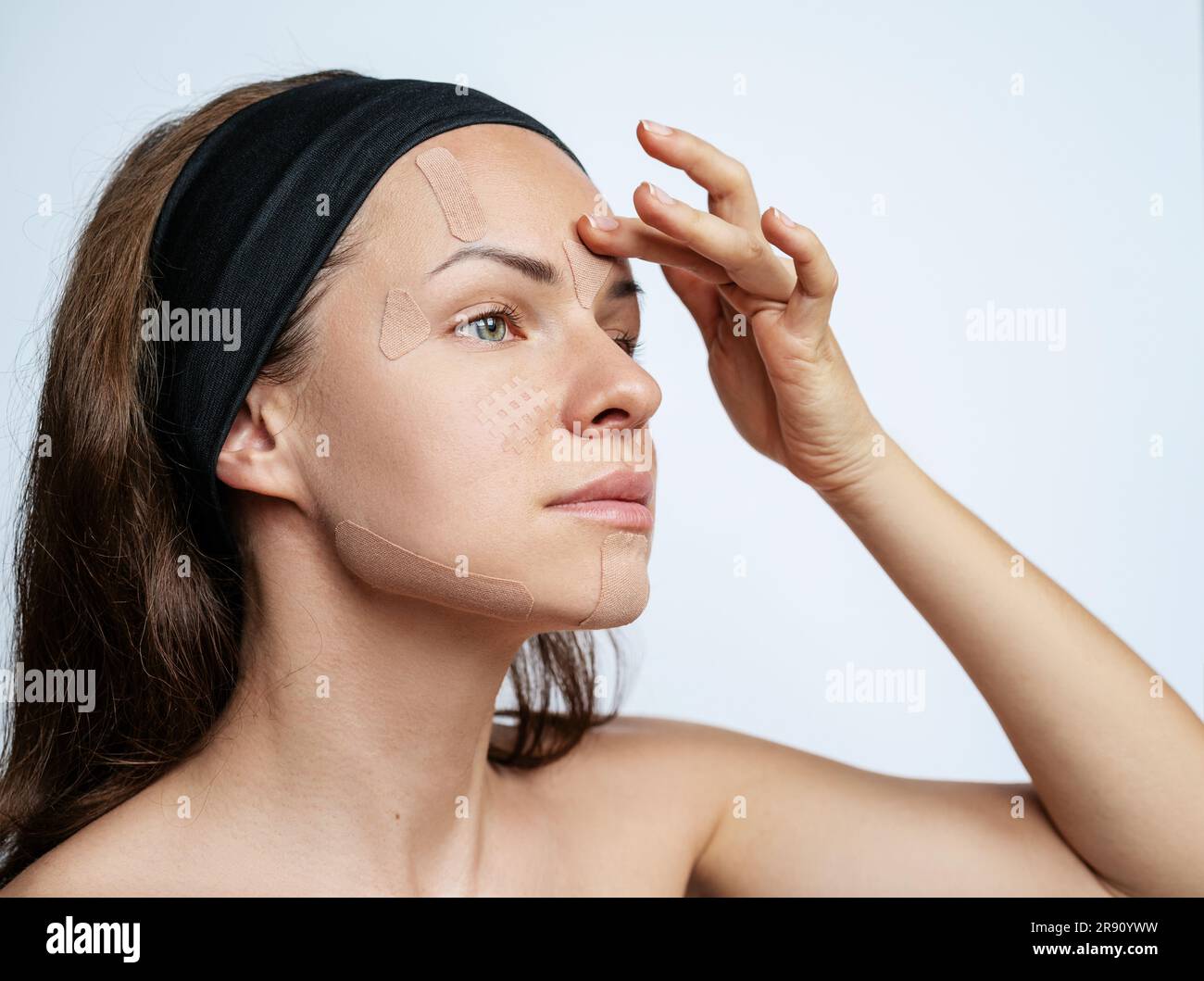Woman beauty model applying facial kinesio tapes on her face, skin ...