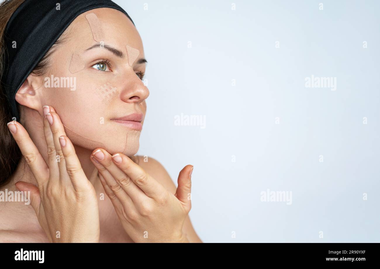 Woman beauty model applying facial kinesio tapes on her face, skin ...