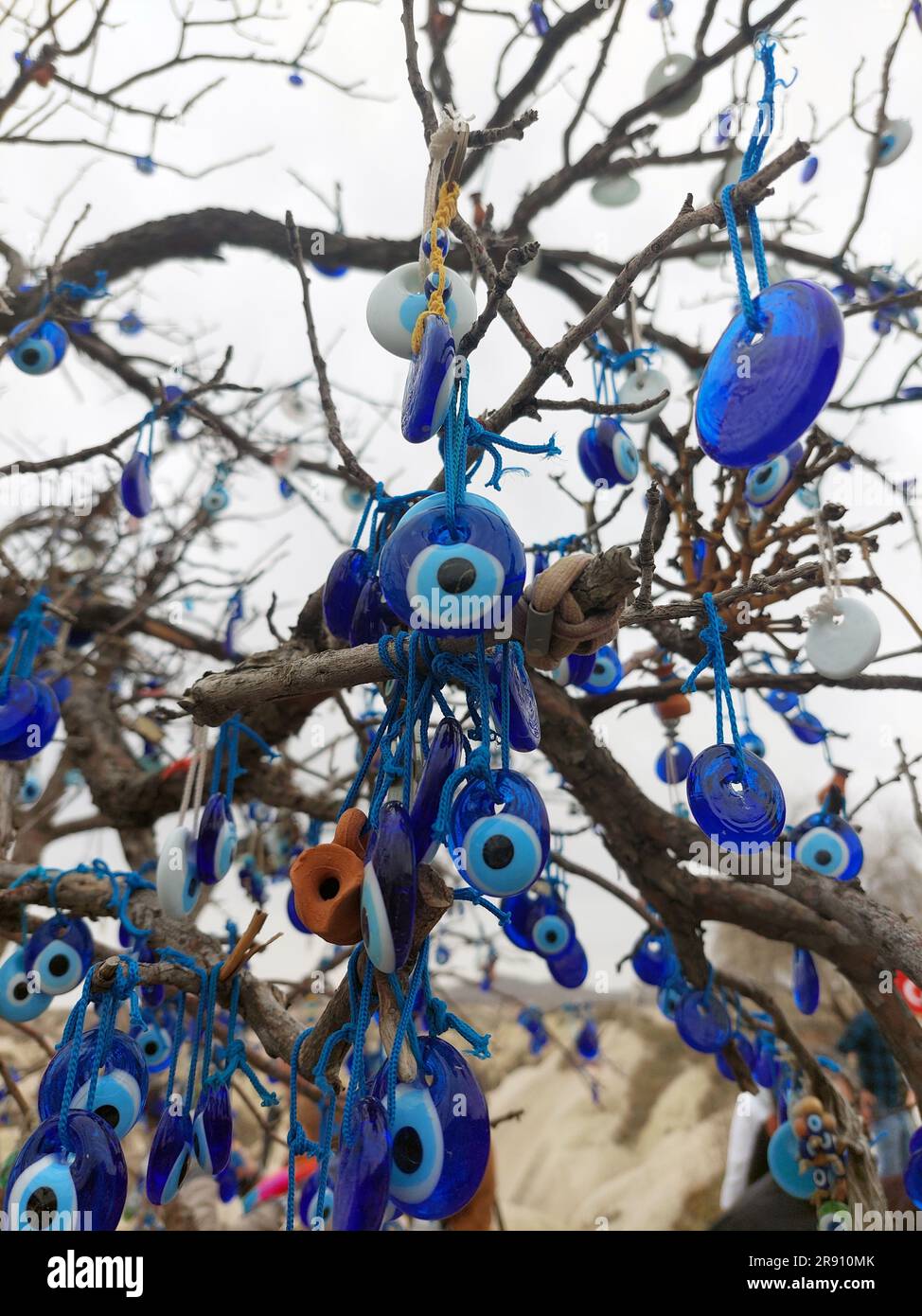 A closeup of tree with multiple blue evil eye charms hanging from it ...