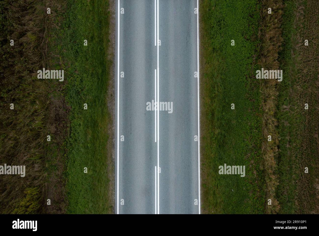 An asphalt road with a continuous lane on one side and a dividing strip ...