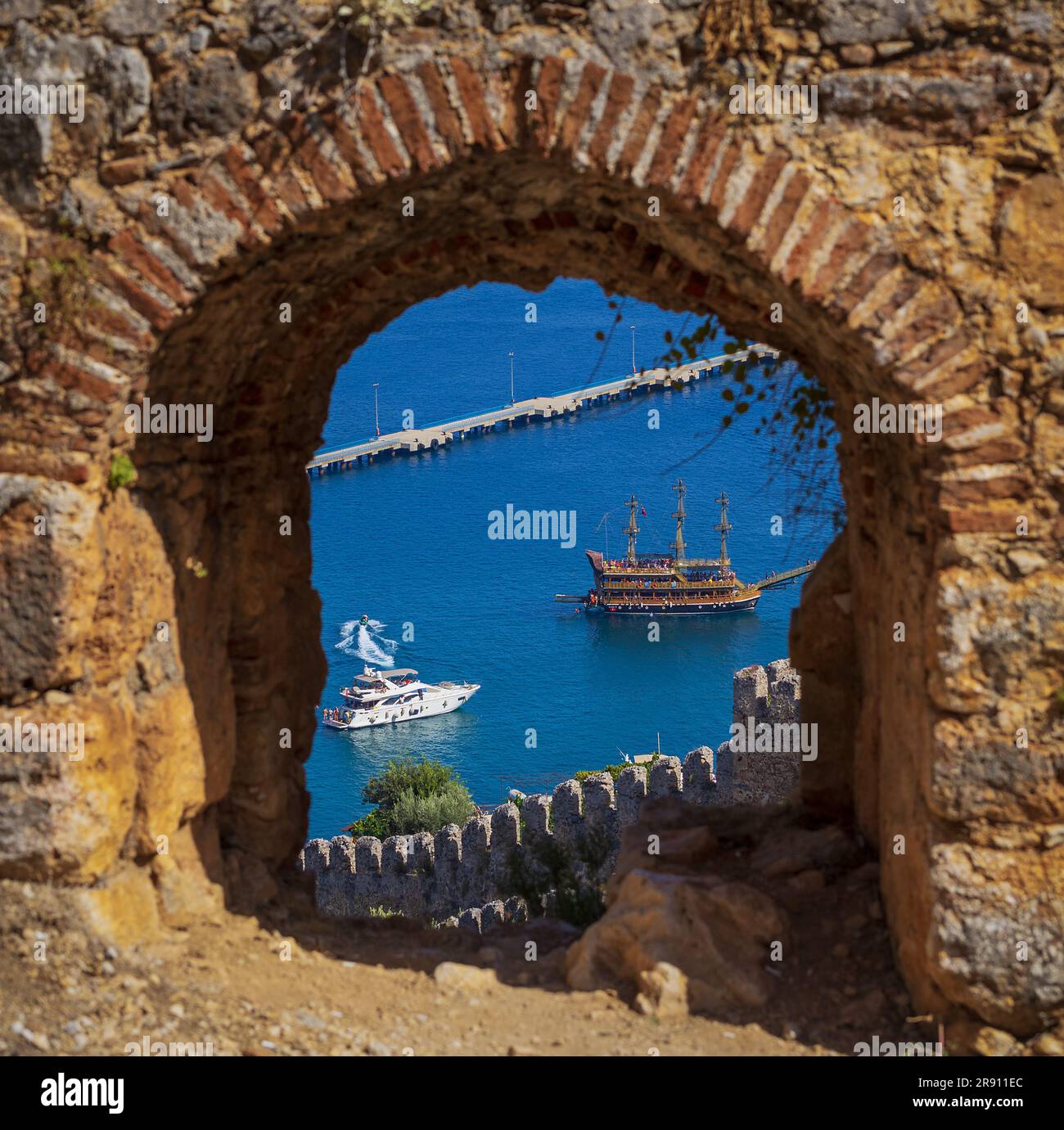 View of tourist ships through the arch of a stone fortress in Alanya ...