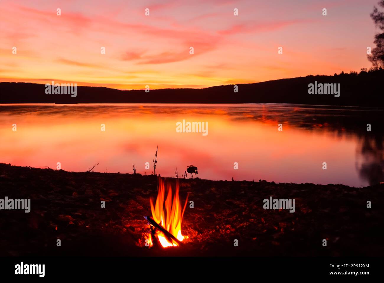 Bonfire. Small campfire with gentle flames beside a lake during a ...