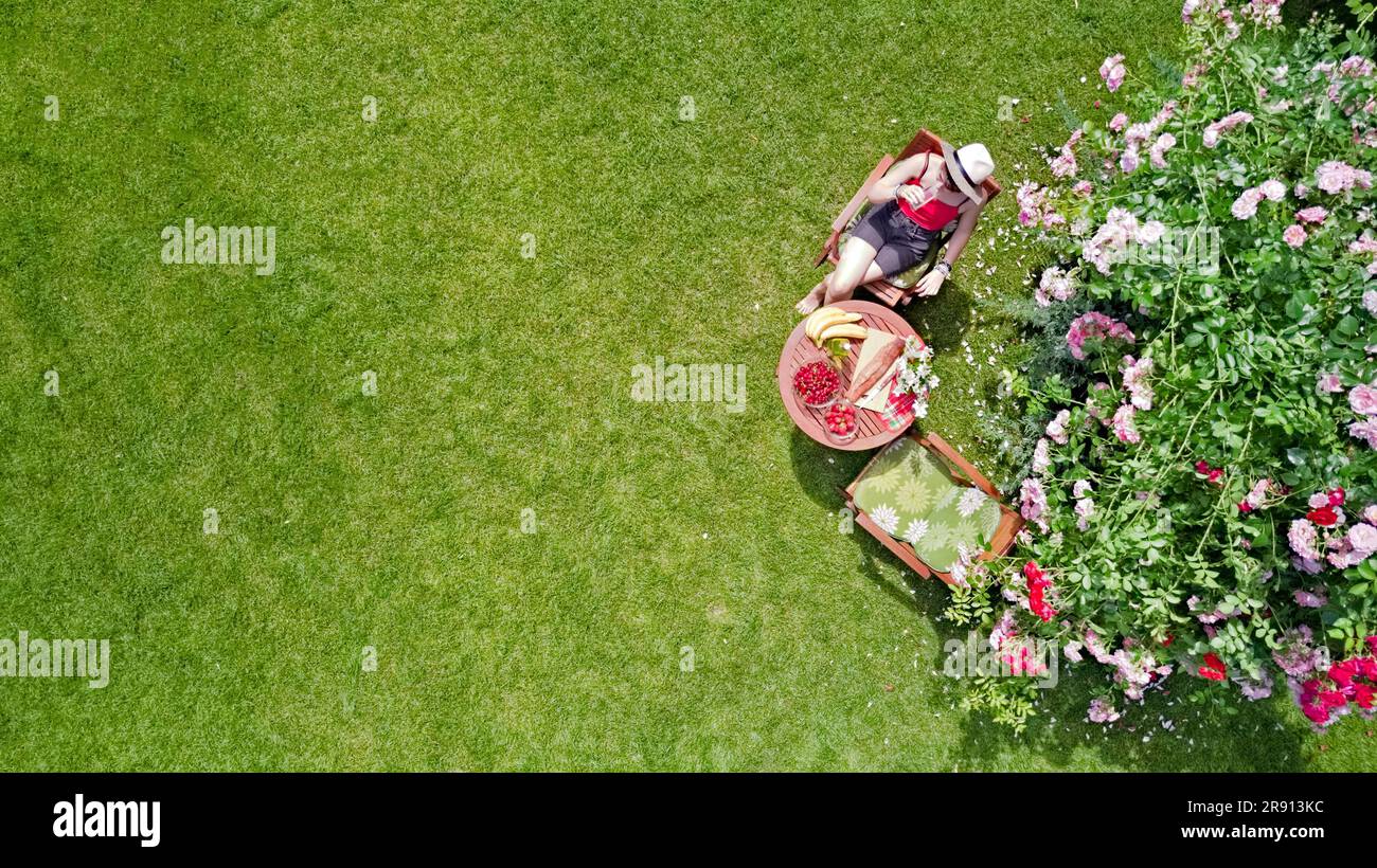 Young girl eating outdoors in summer garden, woman has picnic and ...