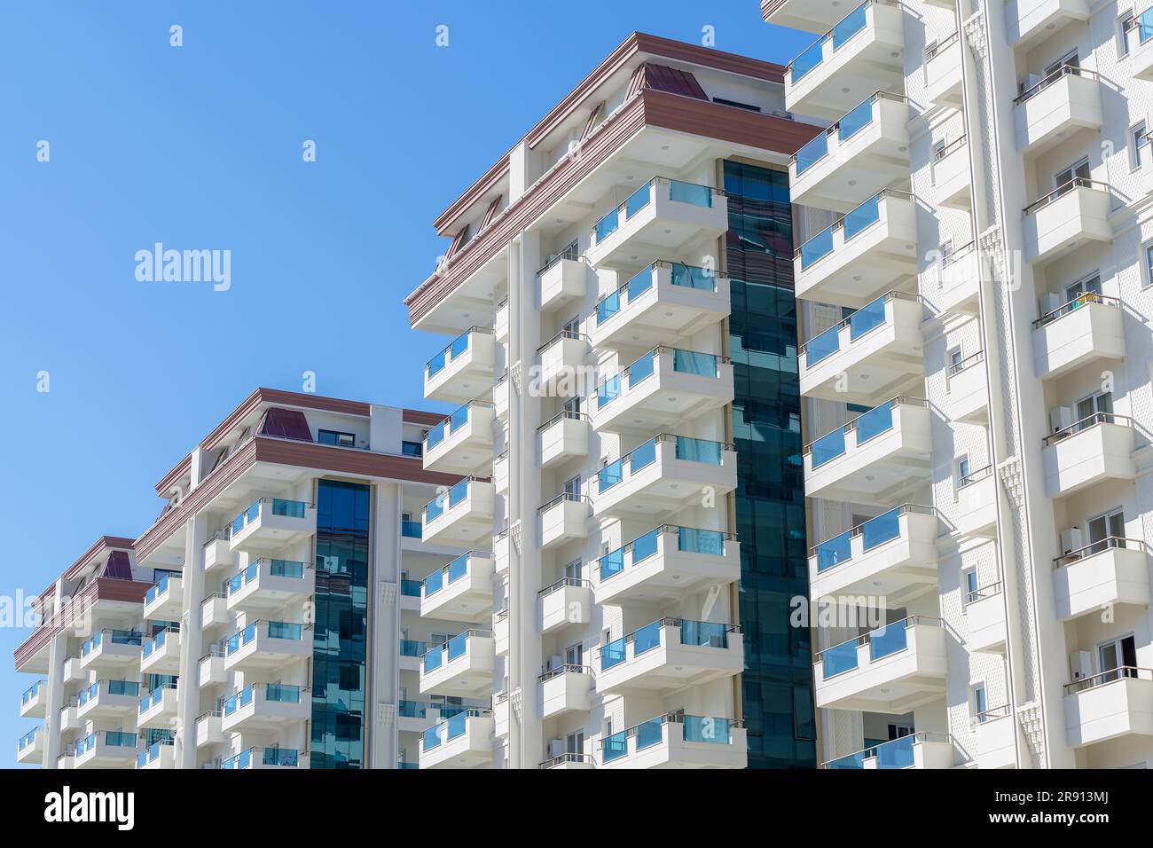 A row of identical buildings with balconies with glass railings. Part ...