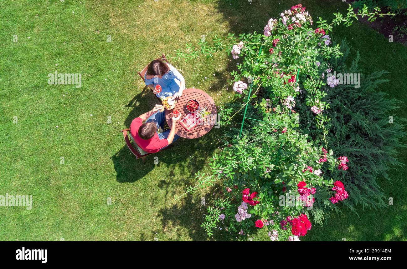Young couple enjoying food and drinks in beautiful roses garden on ...