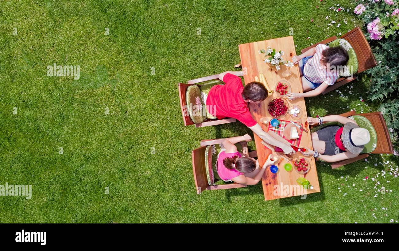 Family and friends eating together outdoors on summer garden party ...