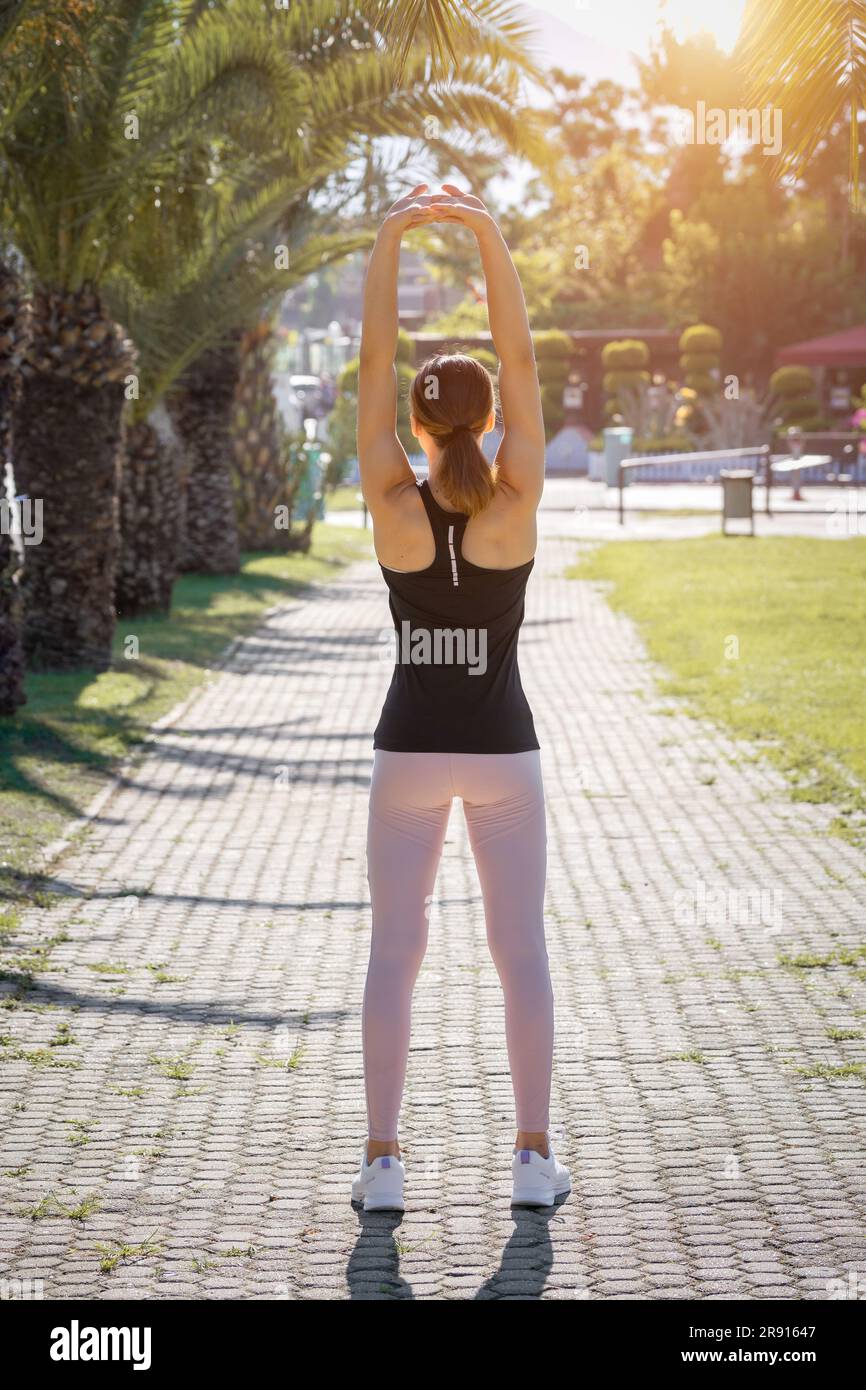 Rear view of a female runner doing stretching before running in the ...
