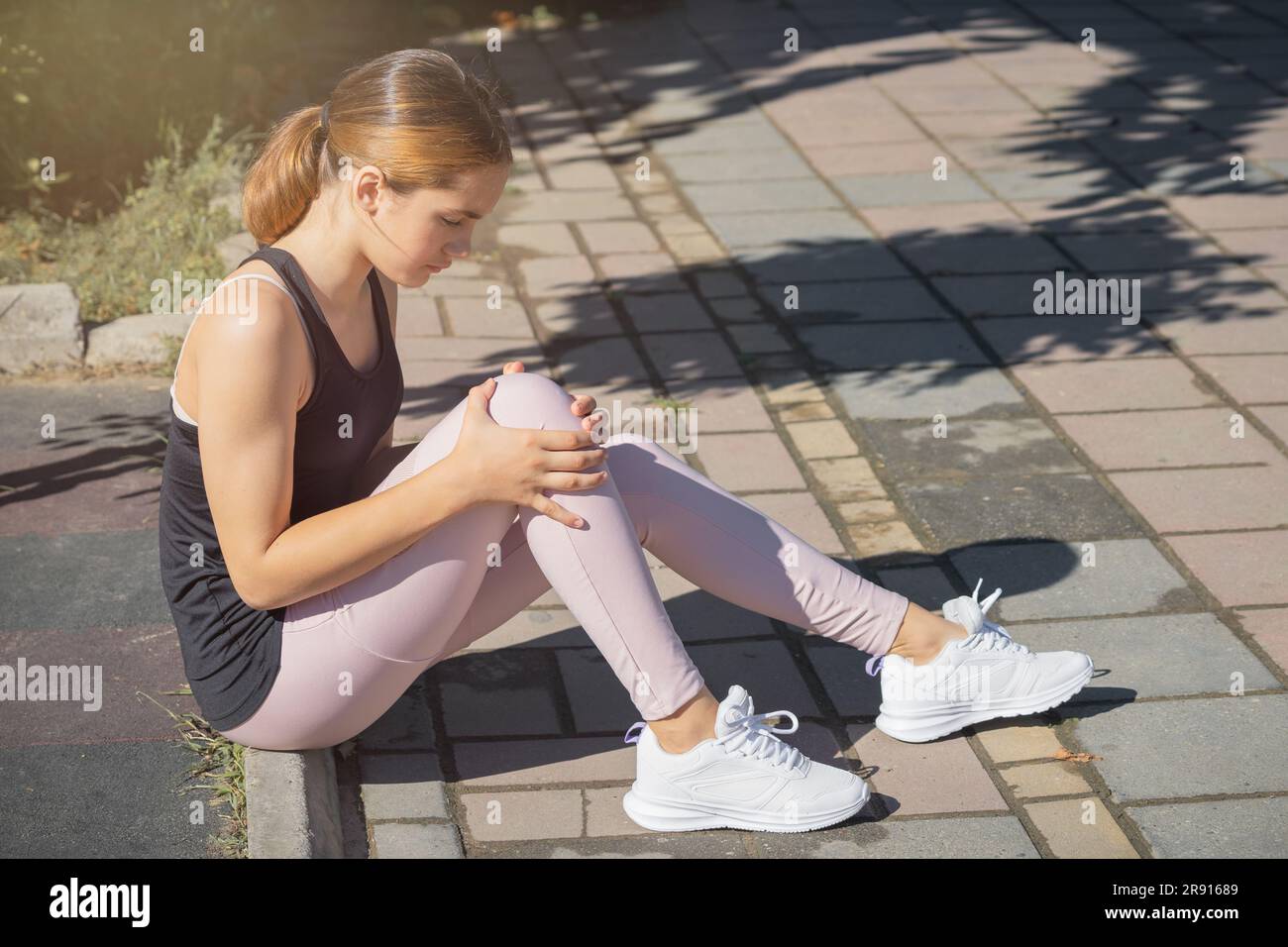 The girl holds an injured knee joint in her hands. Injury while running ...