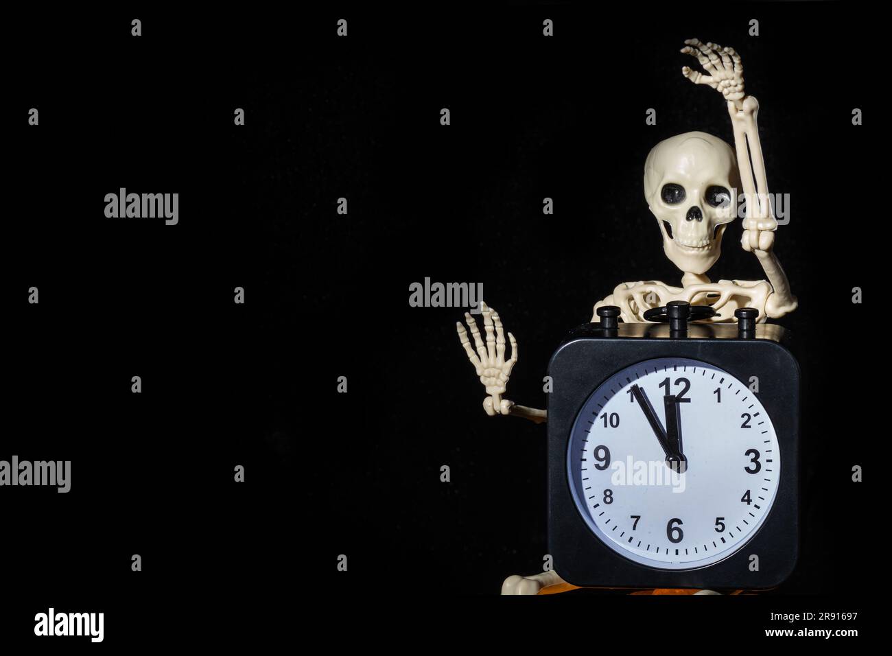 A human skeleton waving his hand, greeting holding an black alarm clock ...