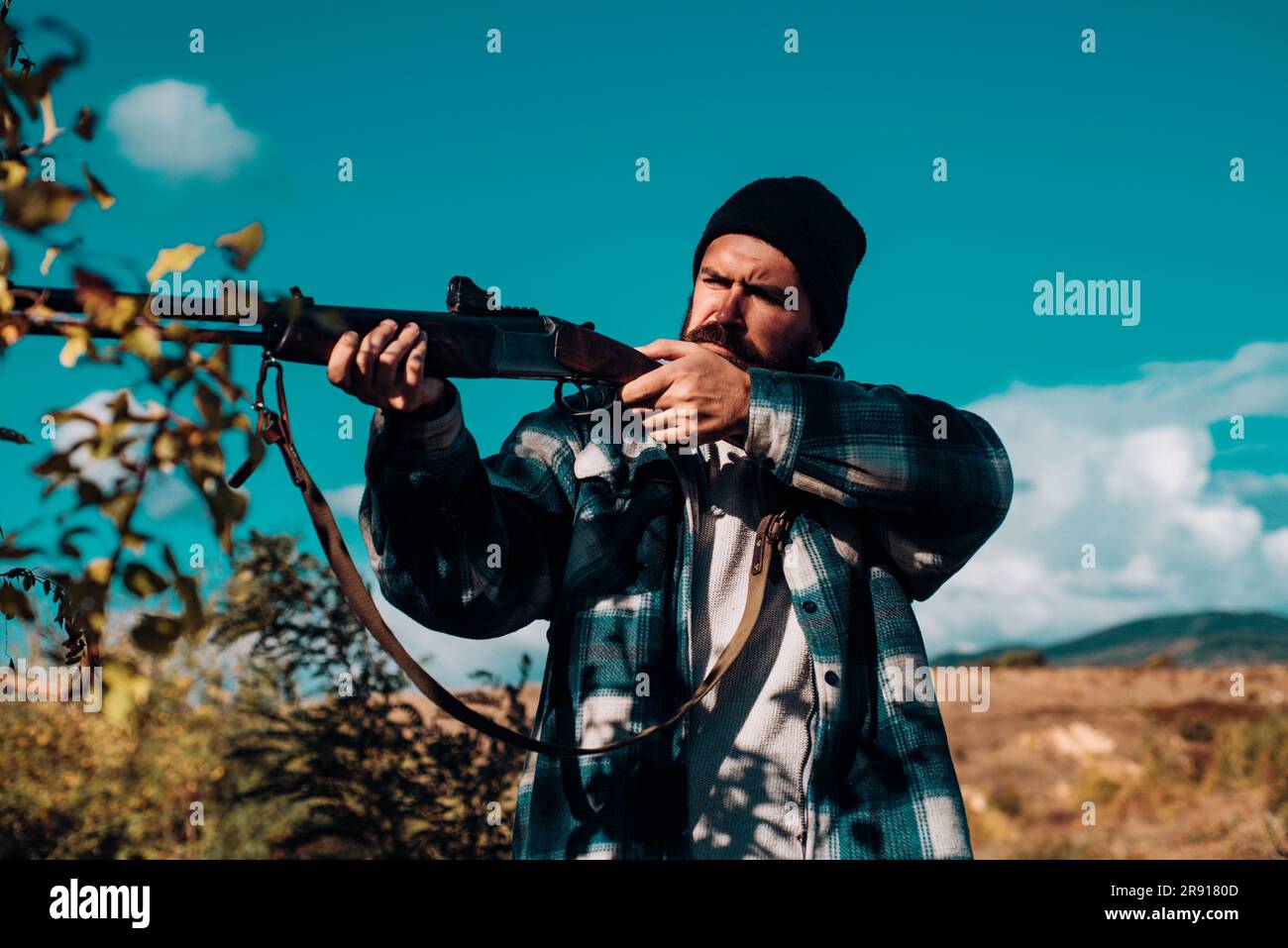 Bearded hunter man holding gun and walking in forest. Hunter with ...