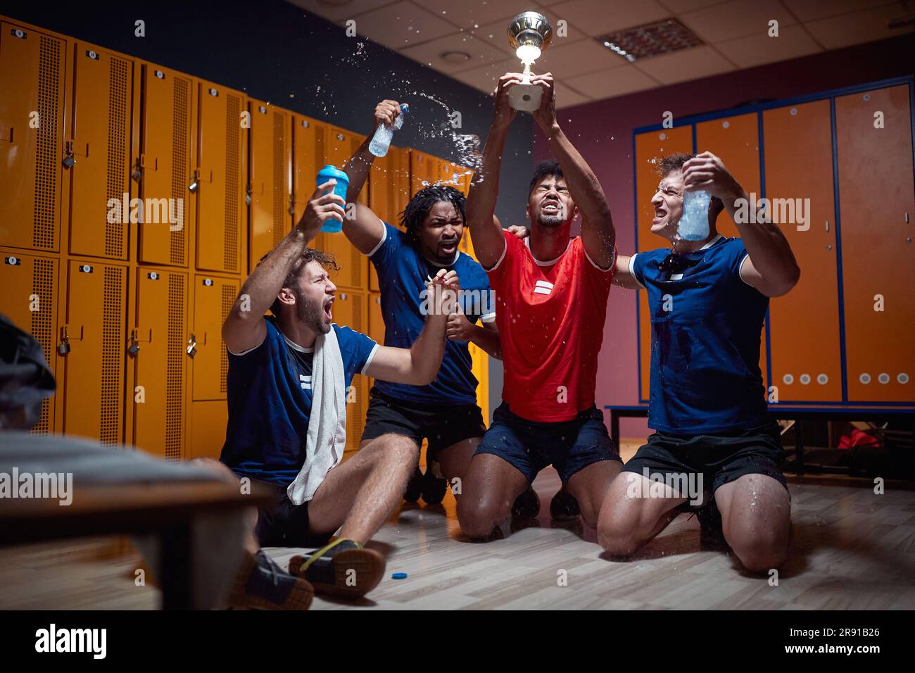 Group of men in dressing room celebrating victory holding gold medal ...
