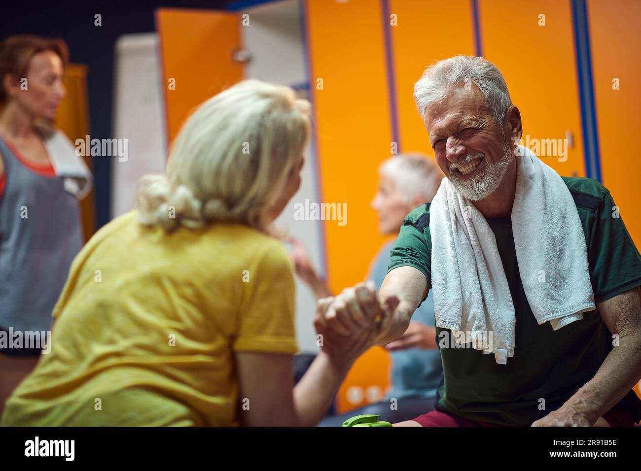 Lovely senior man and woman couple in gym dressing room high fiving ...