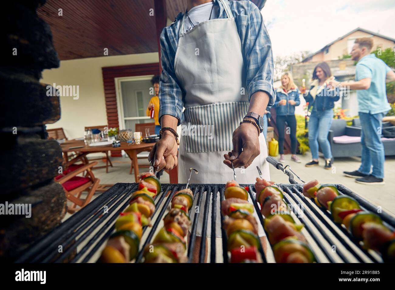Close up view of a sizzling grill. In the foreground, hands expertly ...