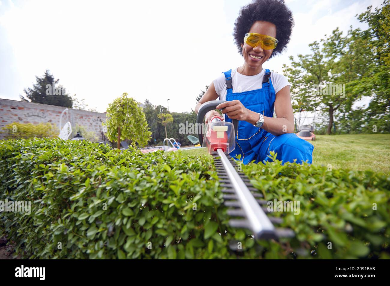 Woman confidently wields a precision trimmer as she skillfully shapes a ...