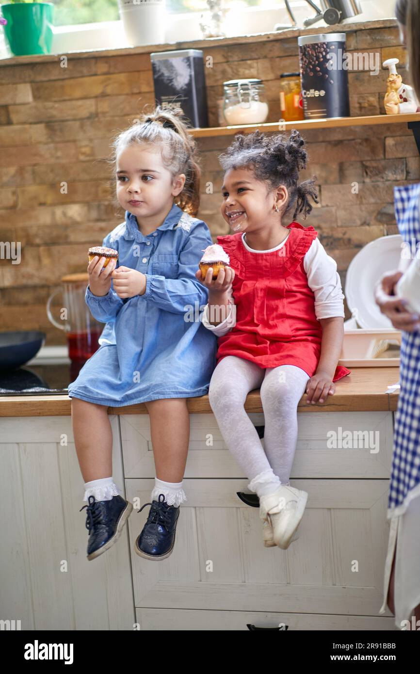 Two young girls are captured in a delightful moment as they sit on the ...