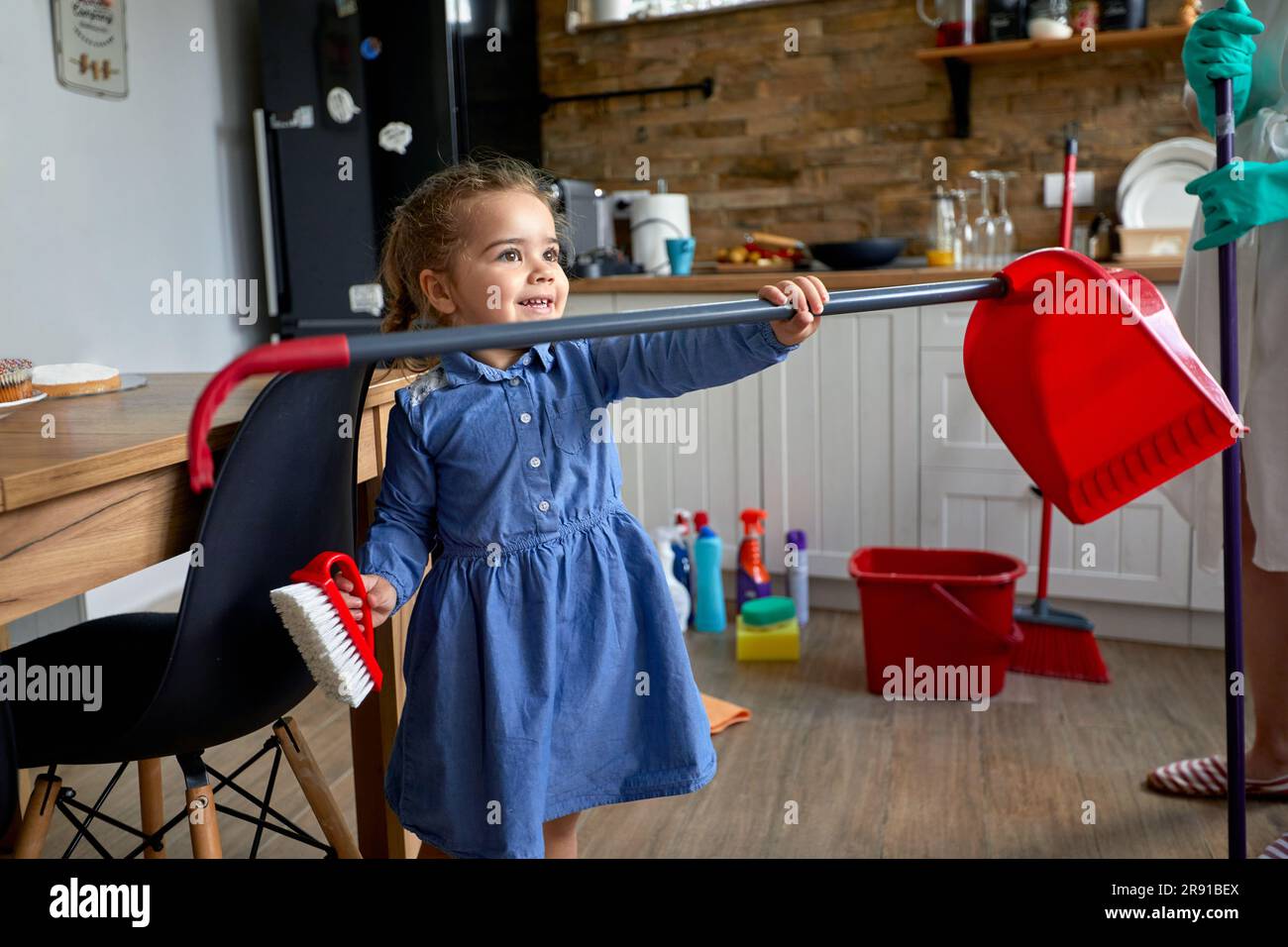 Young girl eagerly lends a hand to her mother during a kitchen cleaning ...