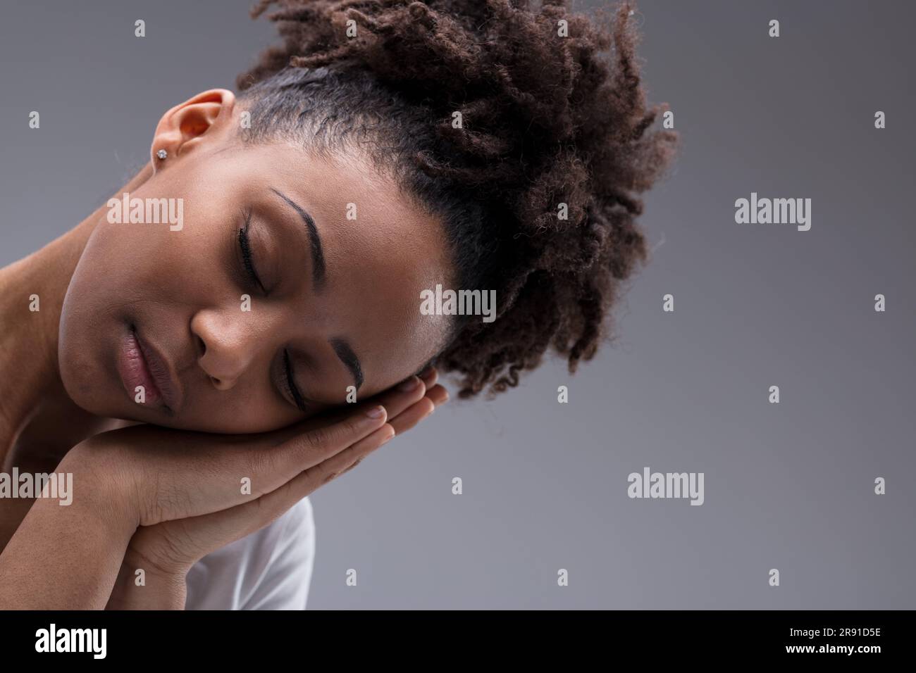 young woman pretends to sleep with hands under her head, eyes closed ...