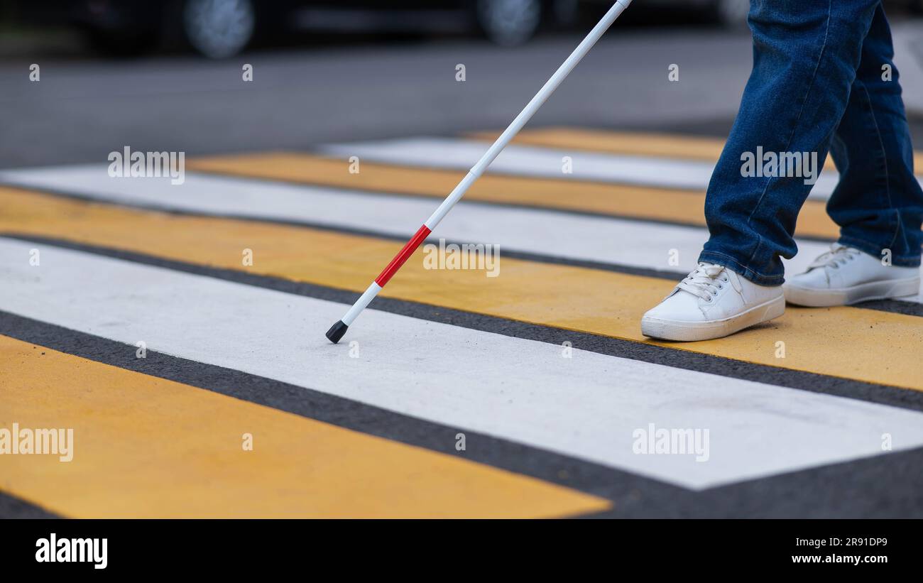 Close-up of the legs of a blind woman crossing the road at a crosswalk ...
