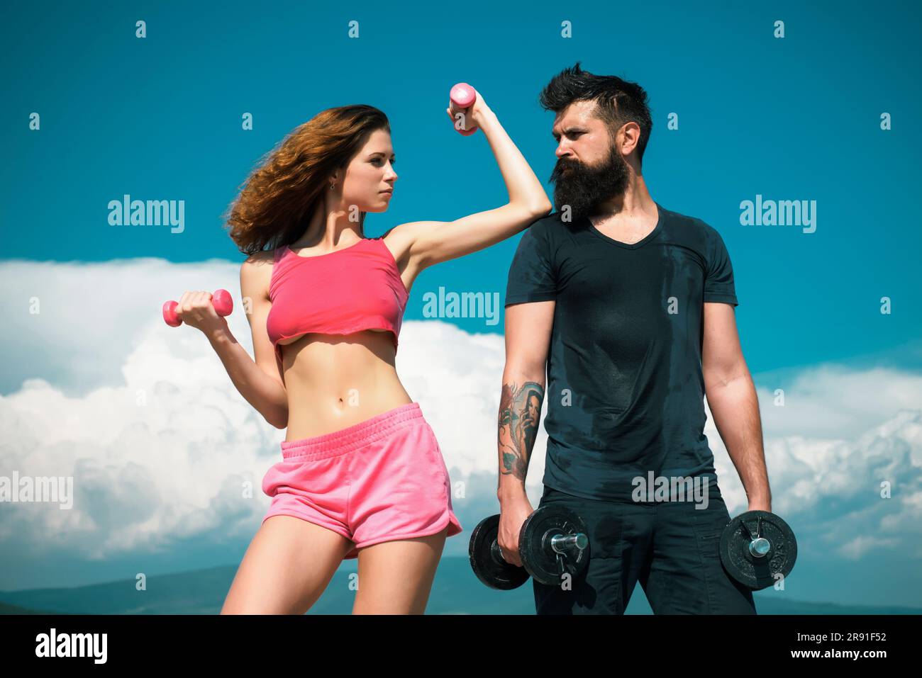 Sporty couple working out with dumbbells on sky background. Healthy ...