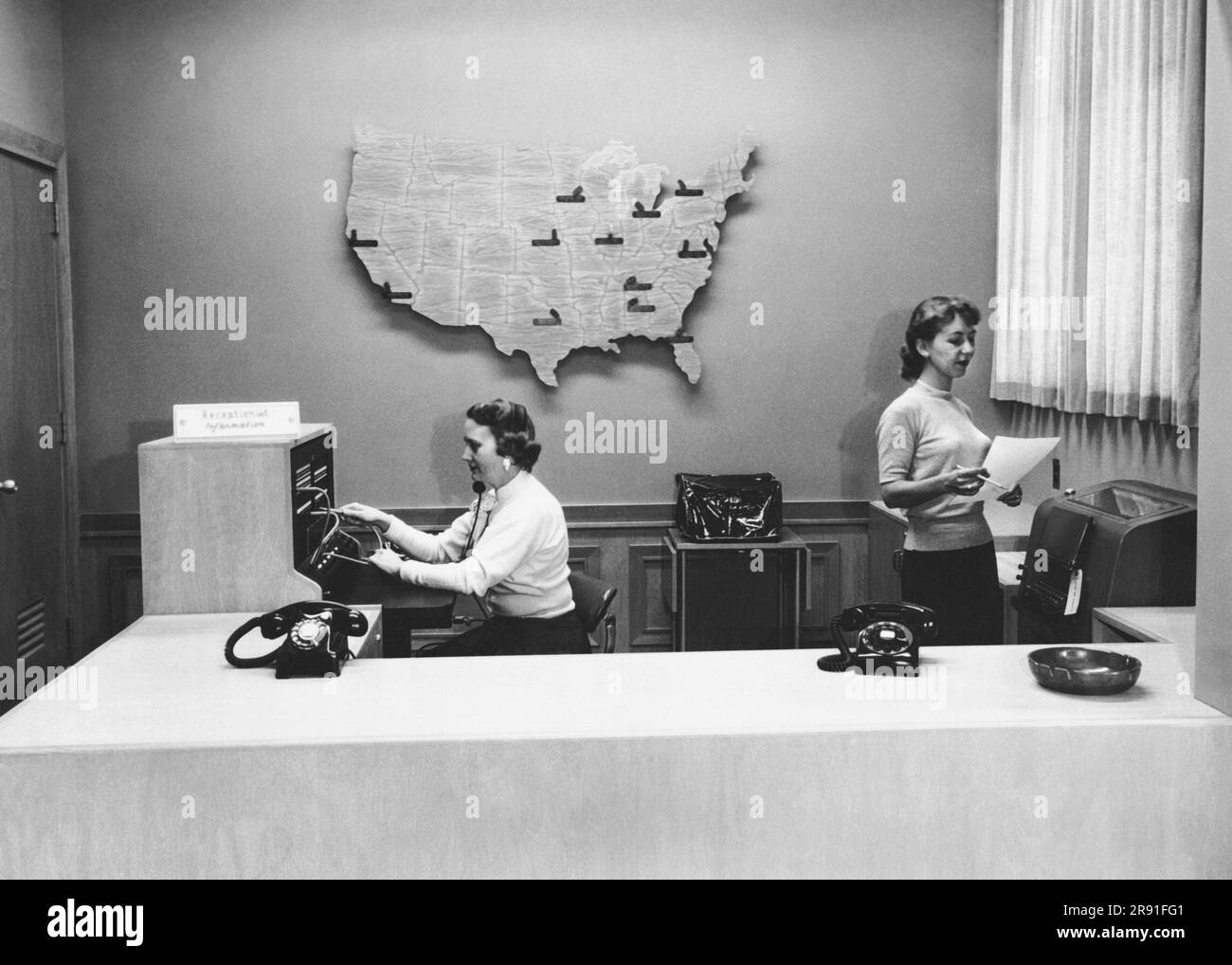 California: c. 1956 Two women working in the receptionist area of a ...