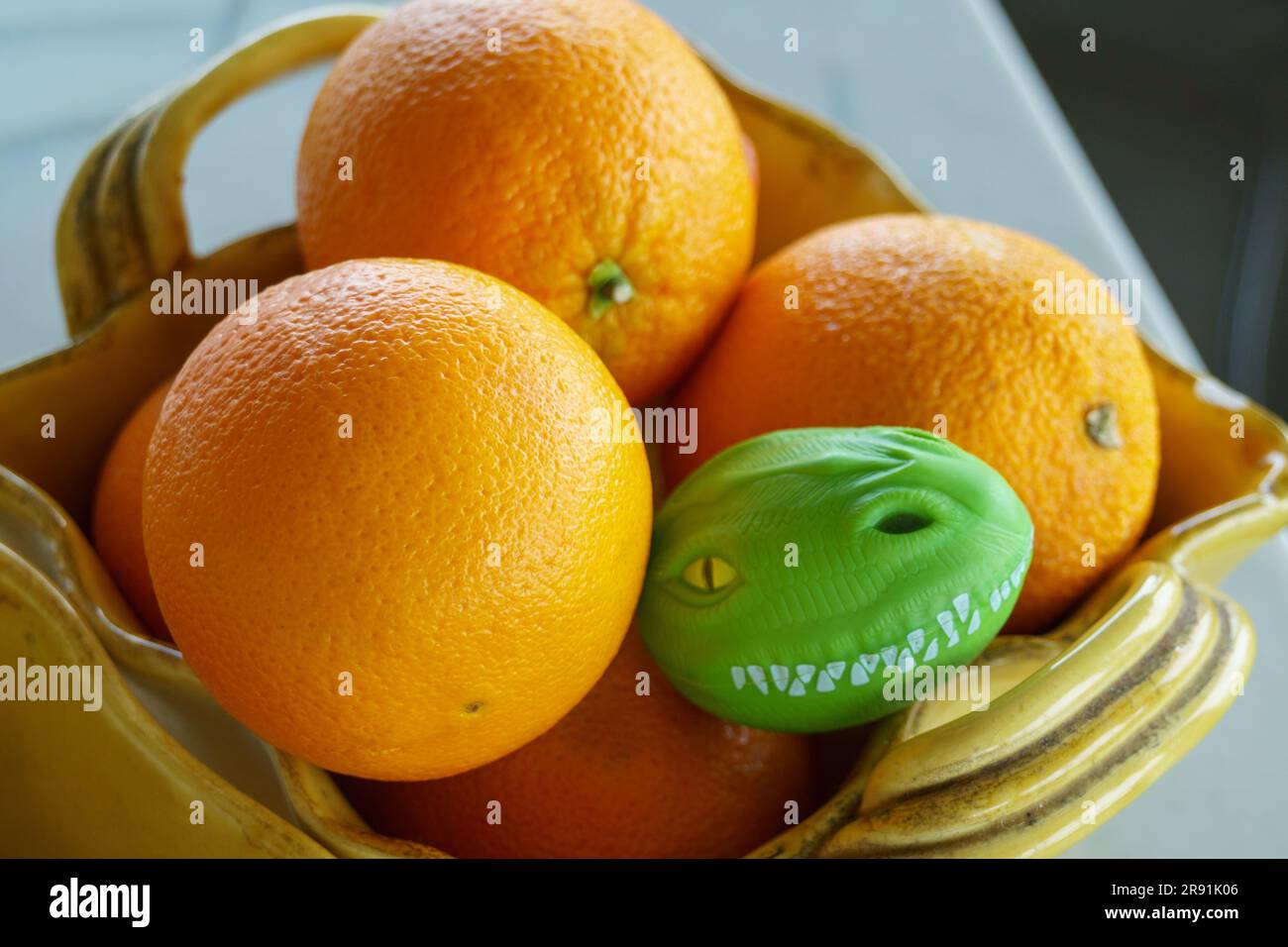 Green tyrannosaurus rex easter egg hidden between oranges in a basket ...