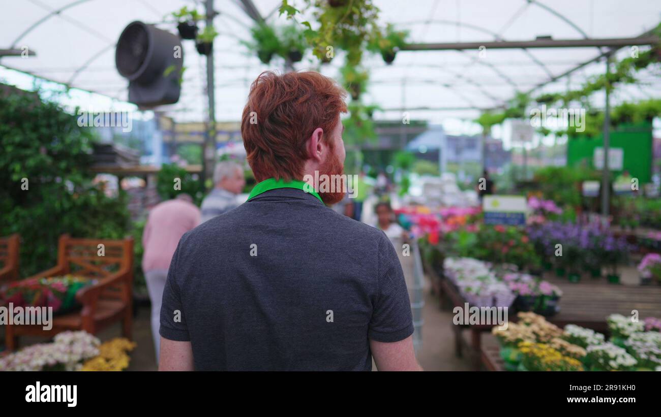 Happy redhead Young entrepreneur walking through Flower Shop. A male ...