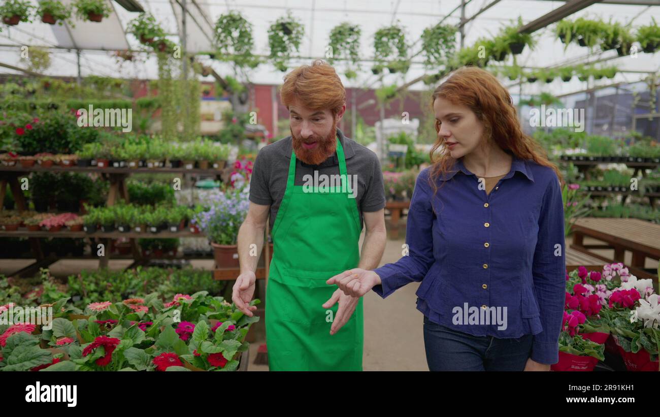 Happy Flower Shop Employee helping customer to guy flower while walking ...