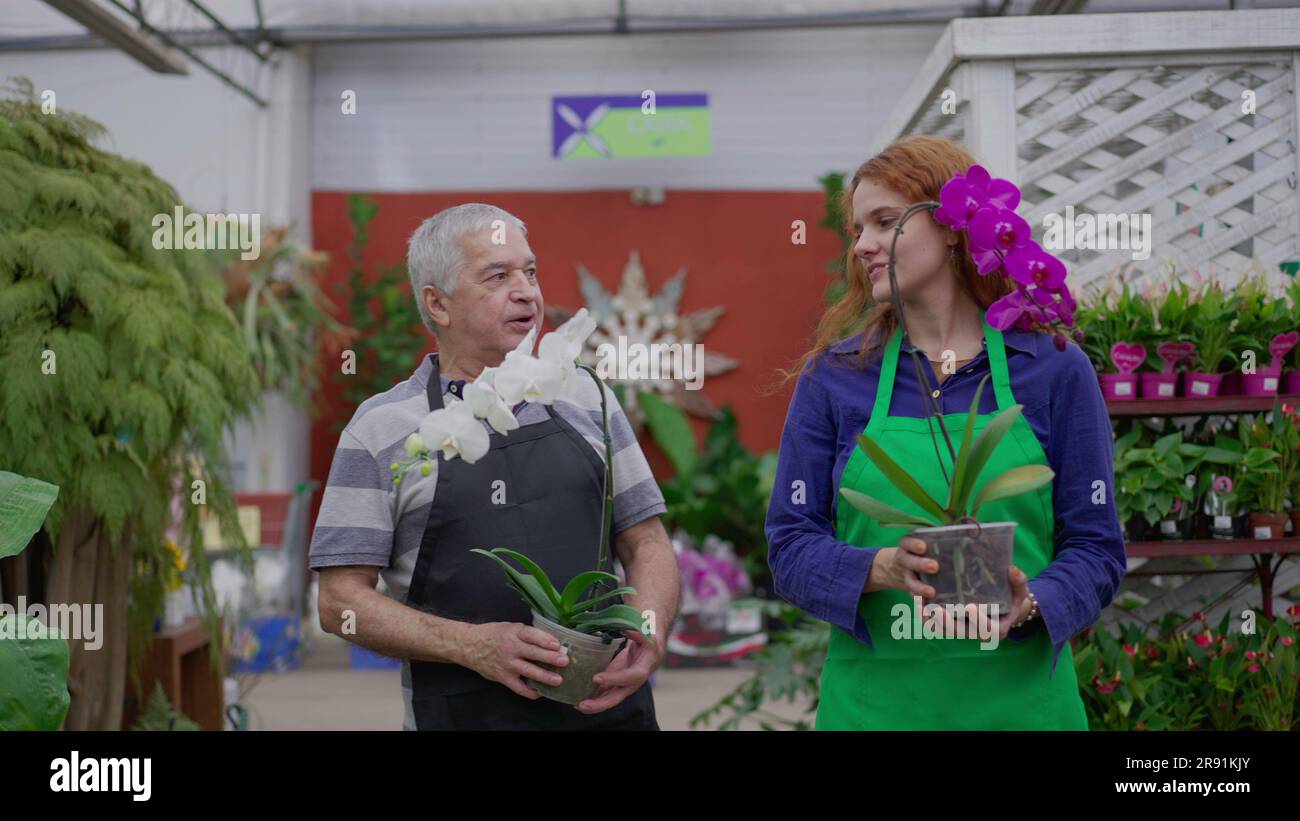 Horticulture employees walking with flowers in shop's aisle. A young ...