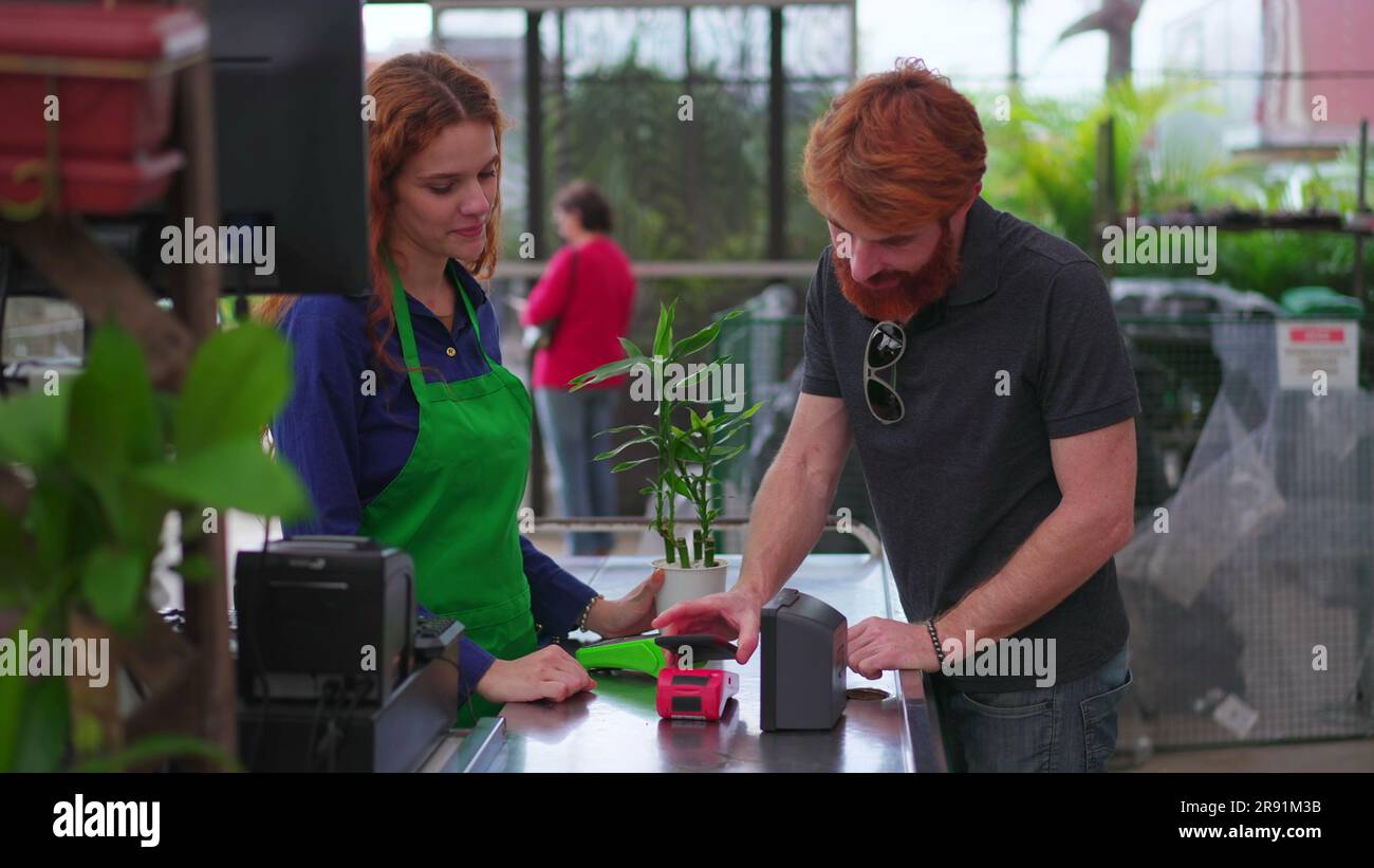 Male Customer Purchasing Plant with contactless payment cellphone at ...