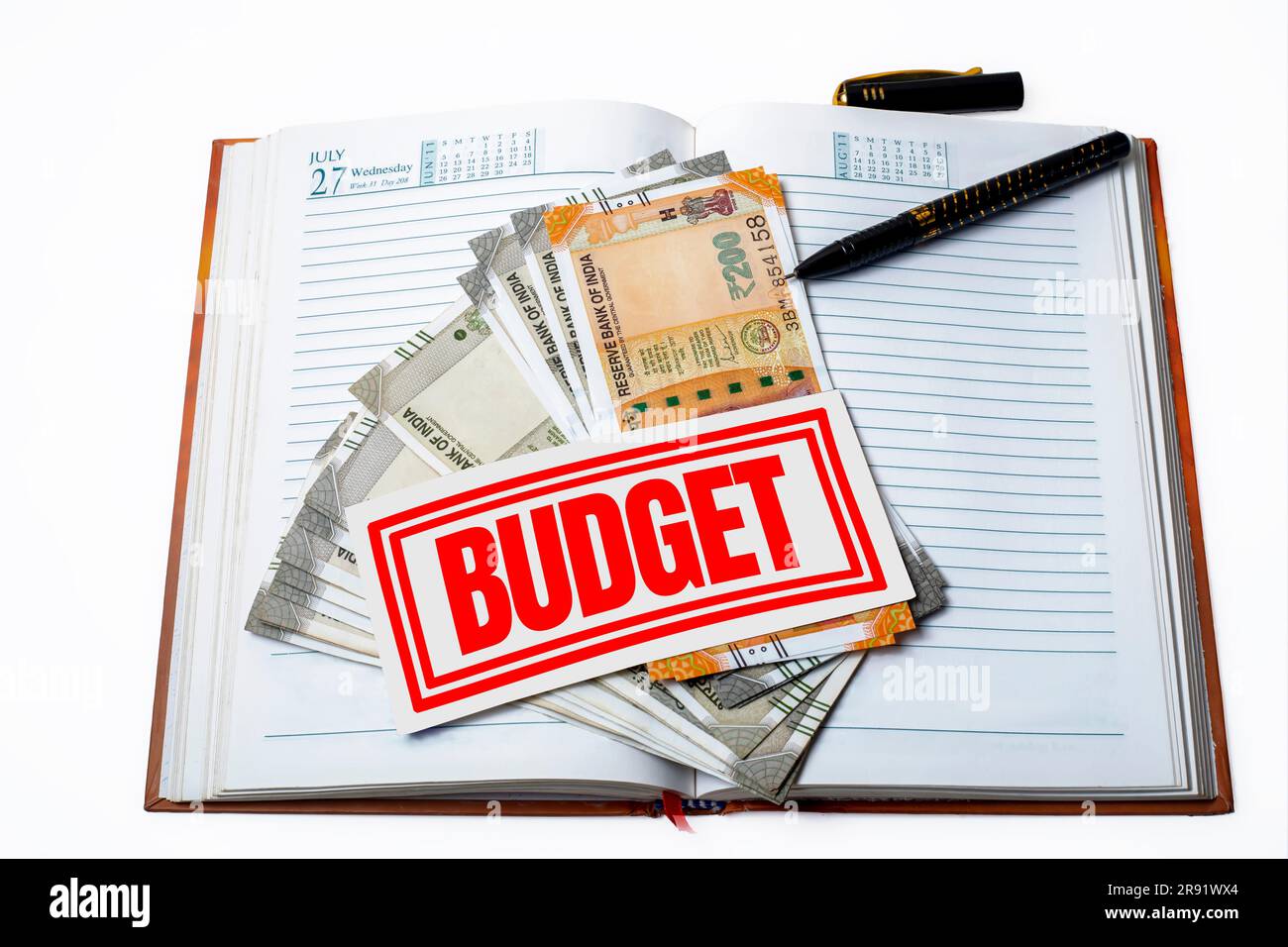 Budget Planning: pile of Indian money with pen over open notebook on a ...