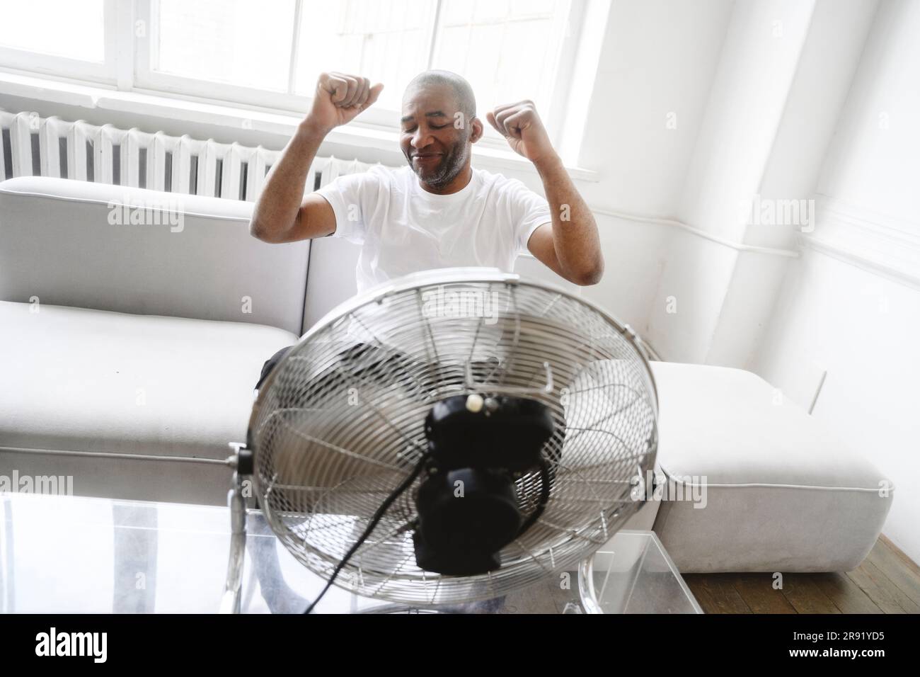 Happy man dancing in front of electric fan at home Stock Photo - Alamy