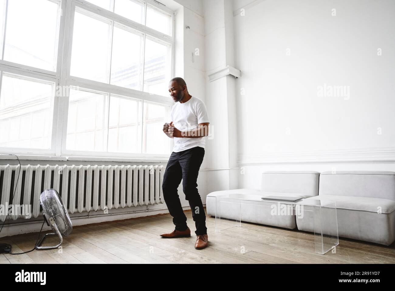 Happy man dancing in front of electric fan at home Stock Photo - Alamy