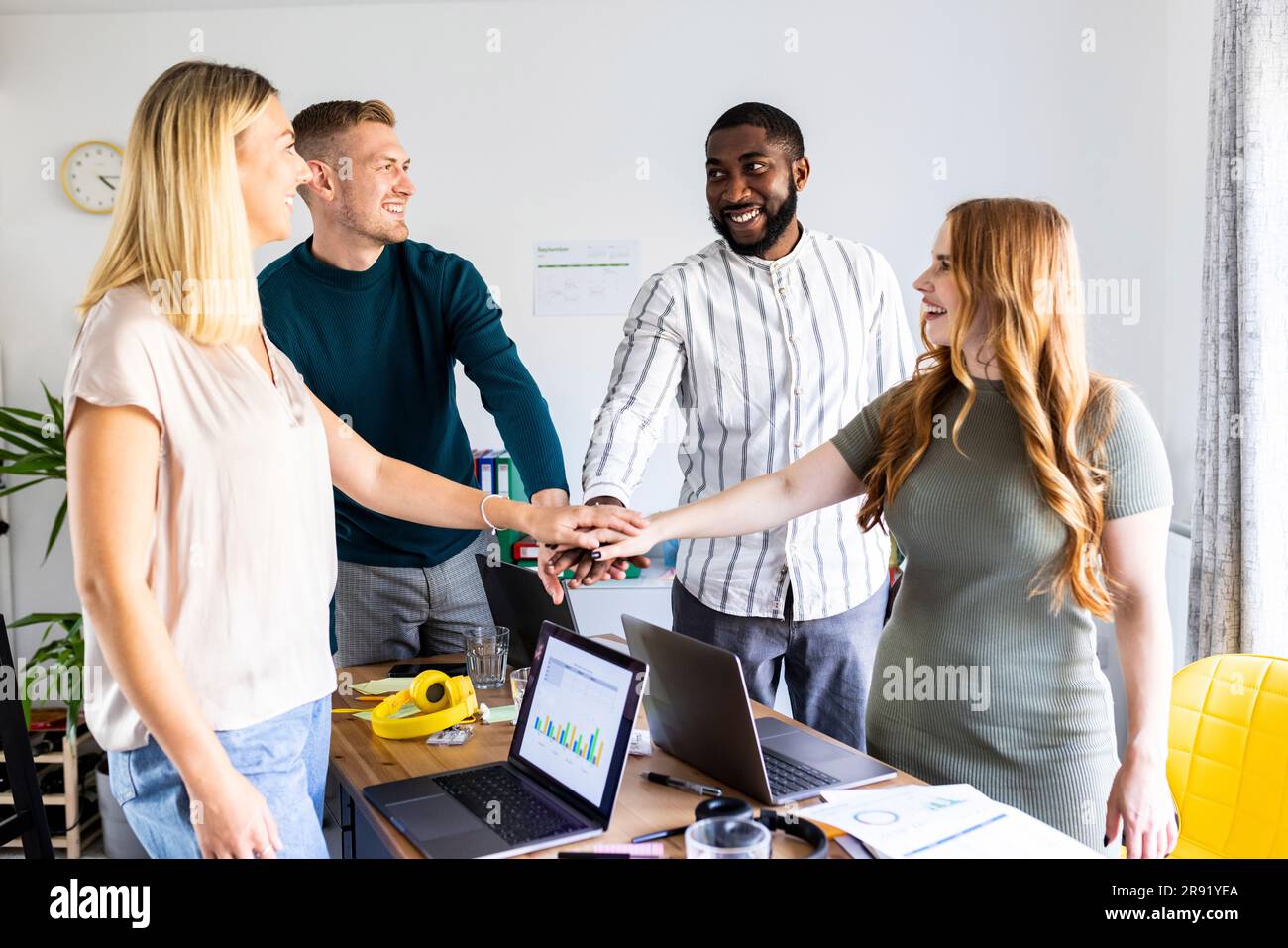 Smiling colleagues stacking hands in meeting at workplace Stock Photo ...